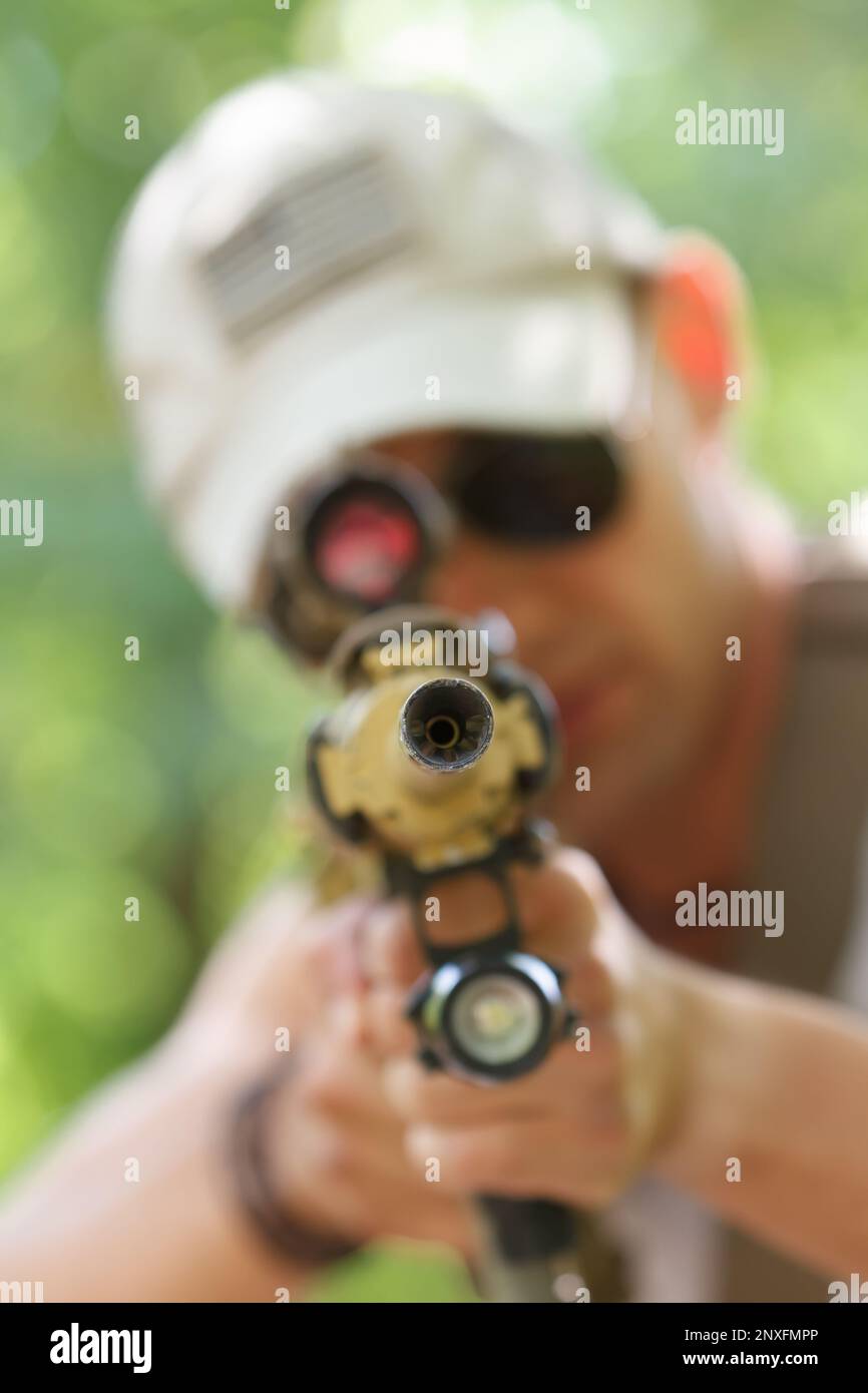 Armed soldier aiming in camera with assault rifle. Focus on barrel of ...