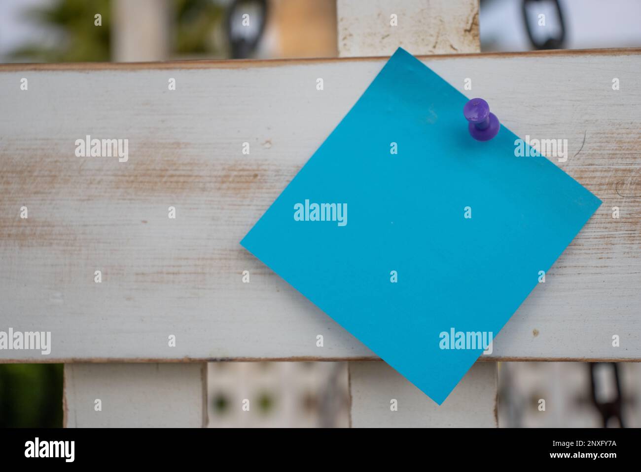 off centre purple map pin blue square paper note on white painted ...