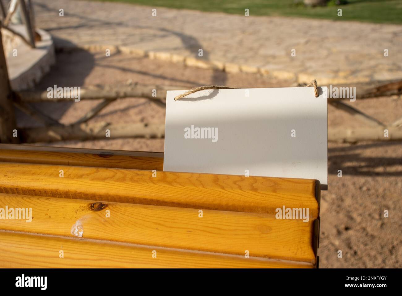 on a park bench white hanging picture sign with empty free space for ...