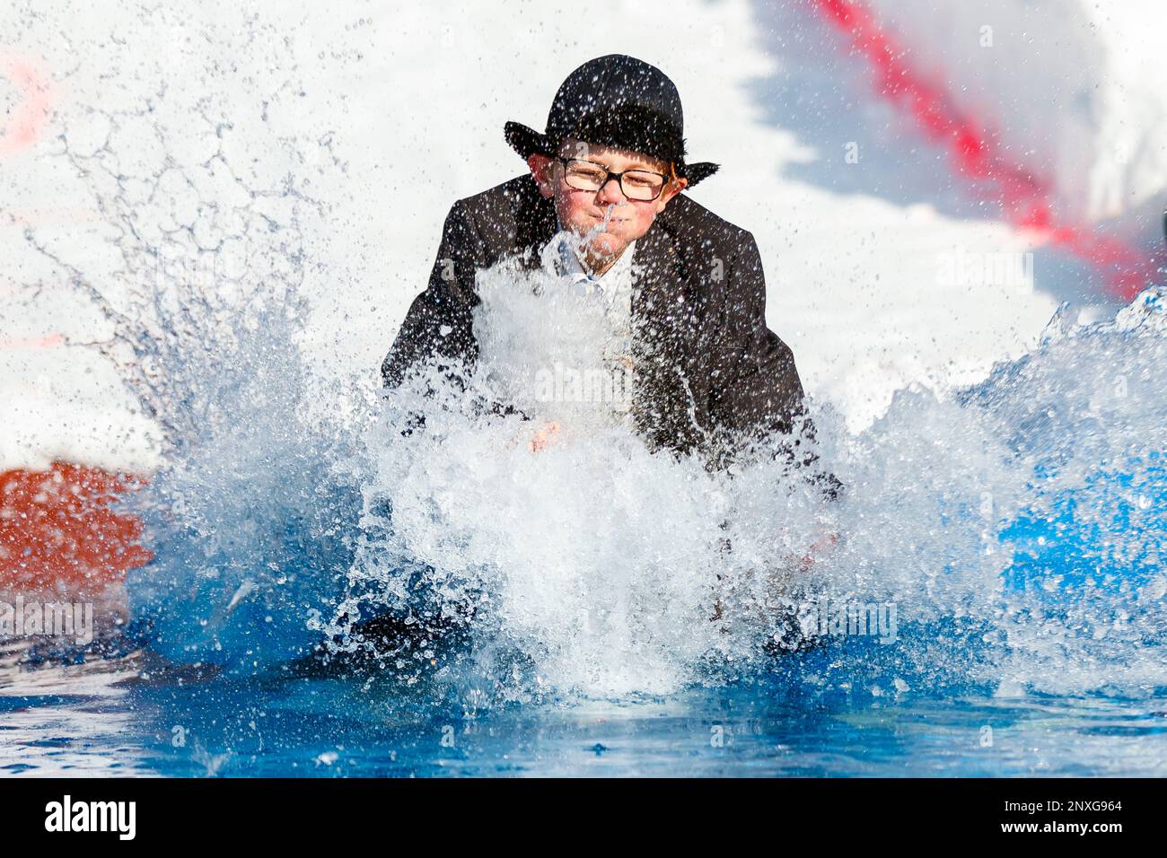 A dressed up contestant hits the pool as he takes part in a waterslide ...