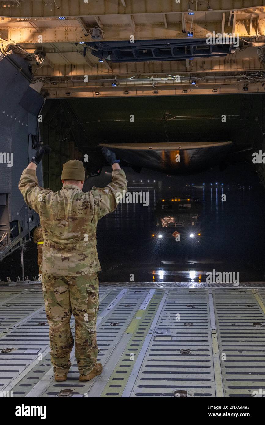 A U.S. Airman guides a M142 High Mobility Artillery Rocket System onto ...