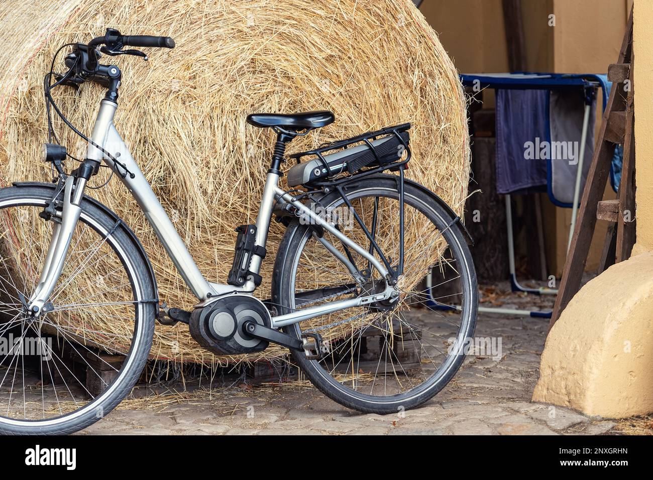 Electric eco green energy power hybrid e-bike parked against big hay ...