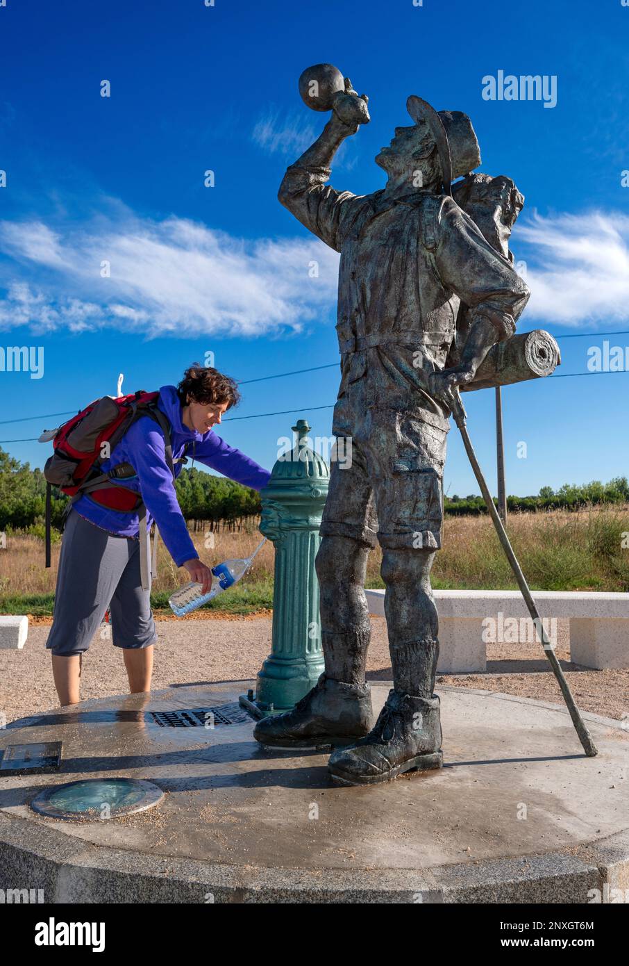 Pilgrim on the Camino de Santiago filling water bottle from fountain ...