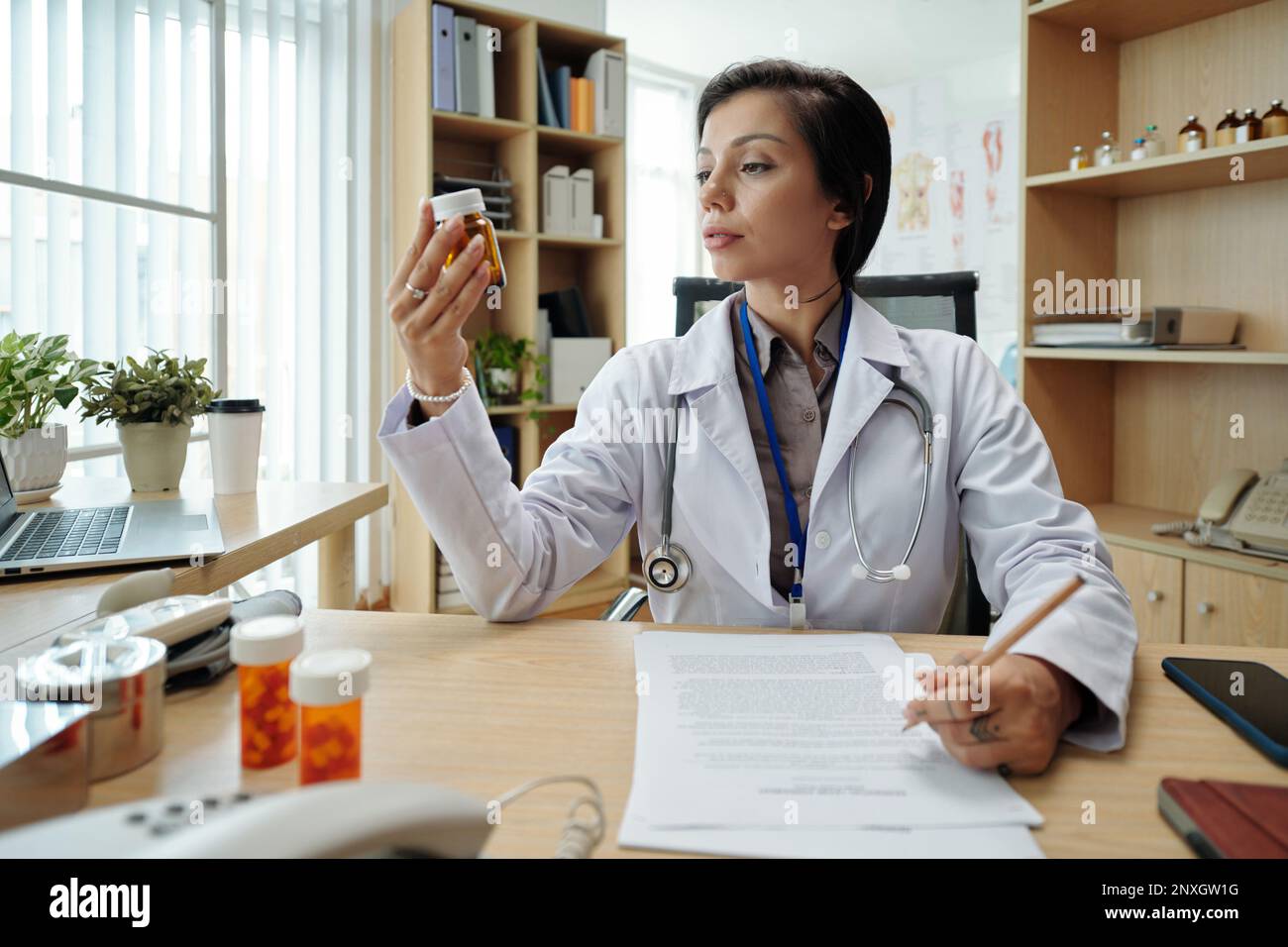 Doctor reading contraindication on package of pill before prescribing ...