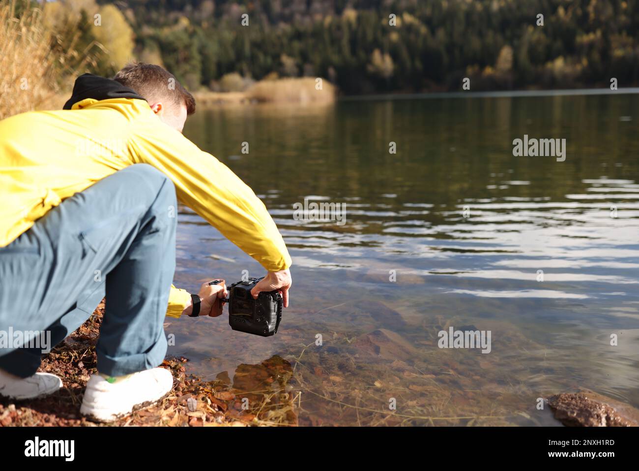 Man taking photo of lake using professional camera Stock Photo - Alamy