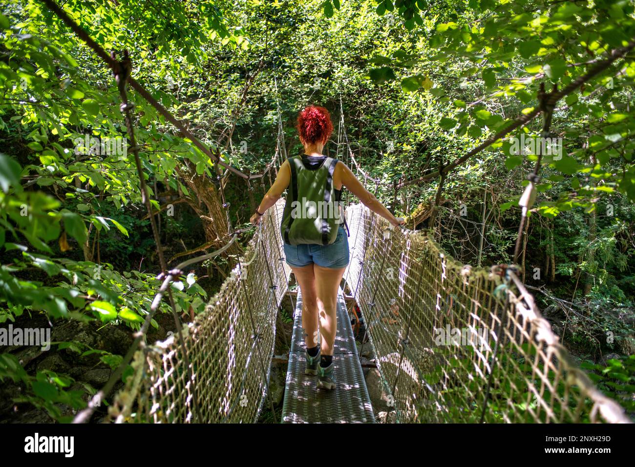 Hiker crossing metal suspension bridge on hiking trail through Gorges ...