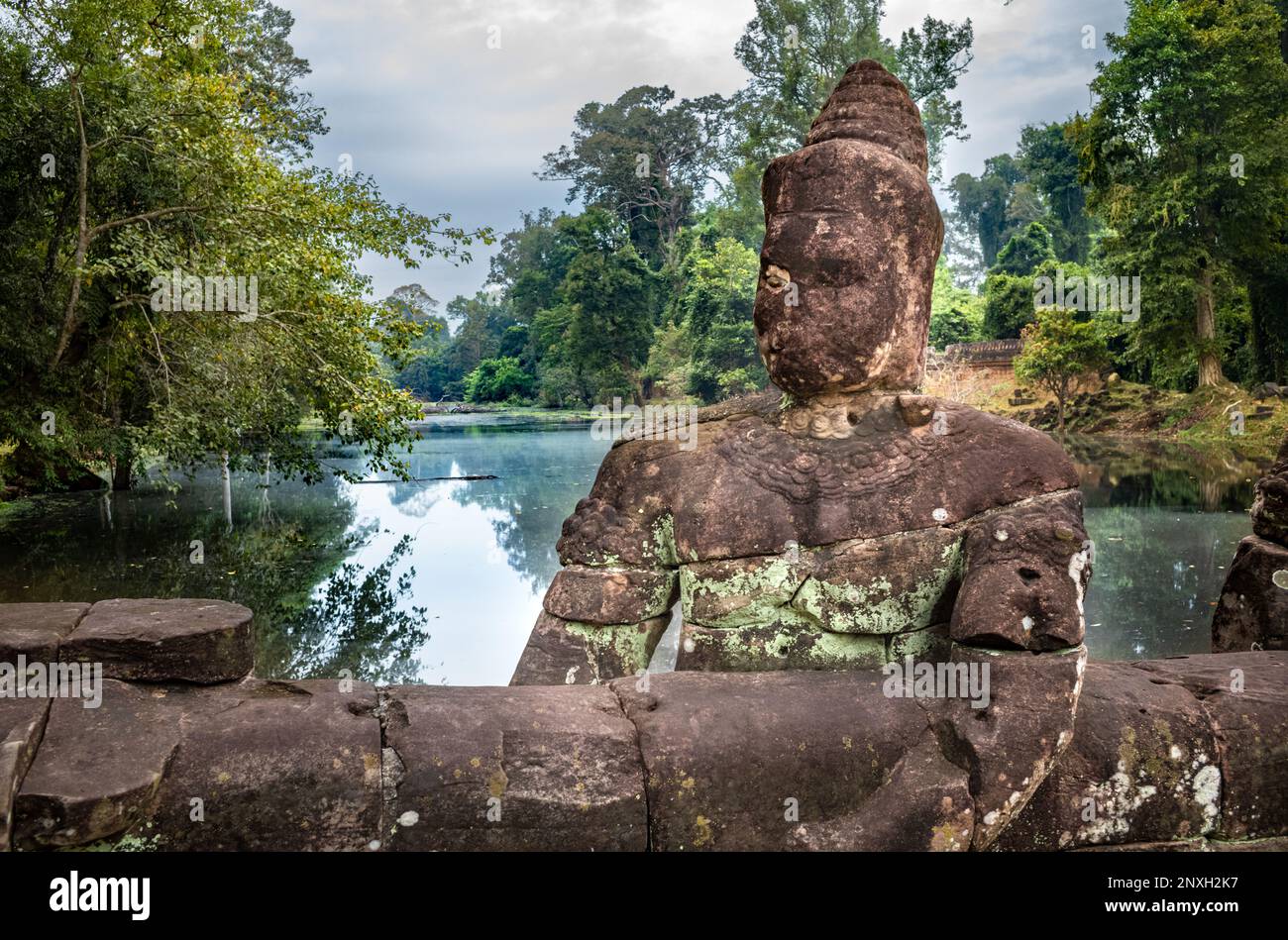 A carved stone figure holding a naga body to form a balustrade over a ...