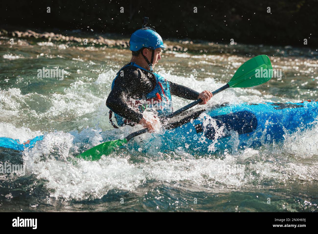 Male recreational athlete paddling carefully over the risky, foamy, and ...