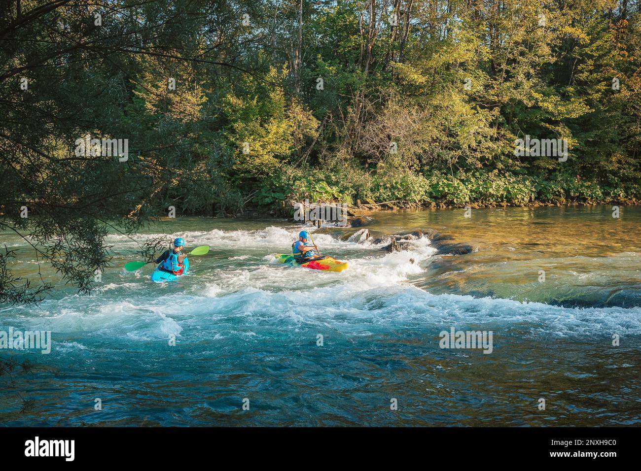 Two kayakers paddling and maneuvering on the fast-moving river with a ...