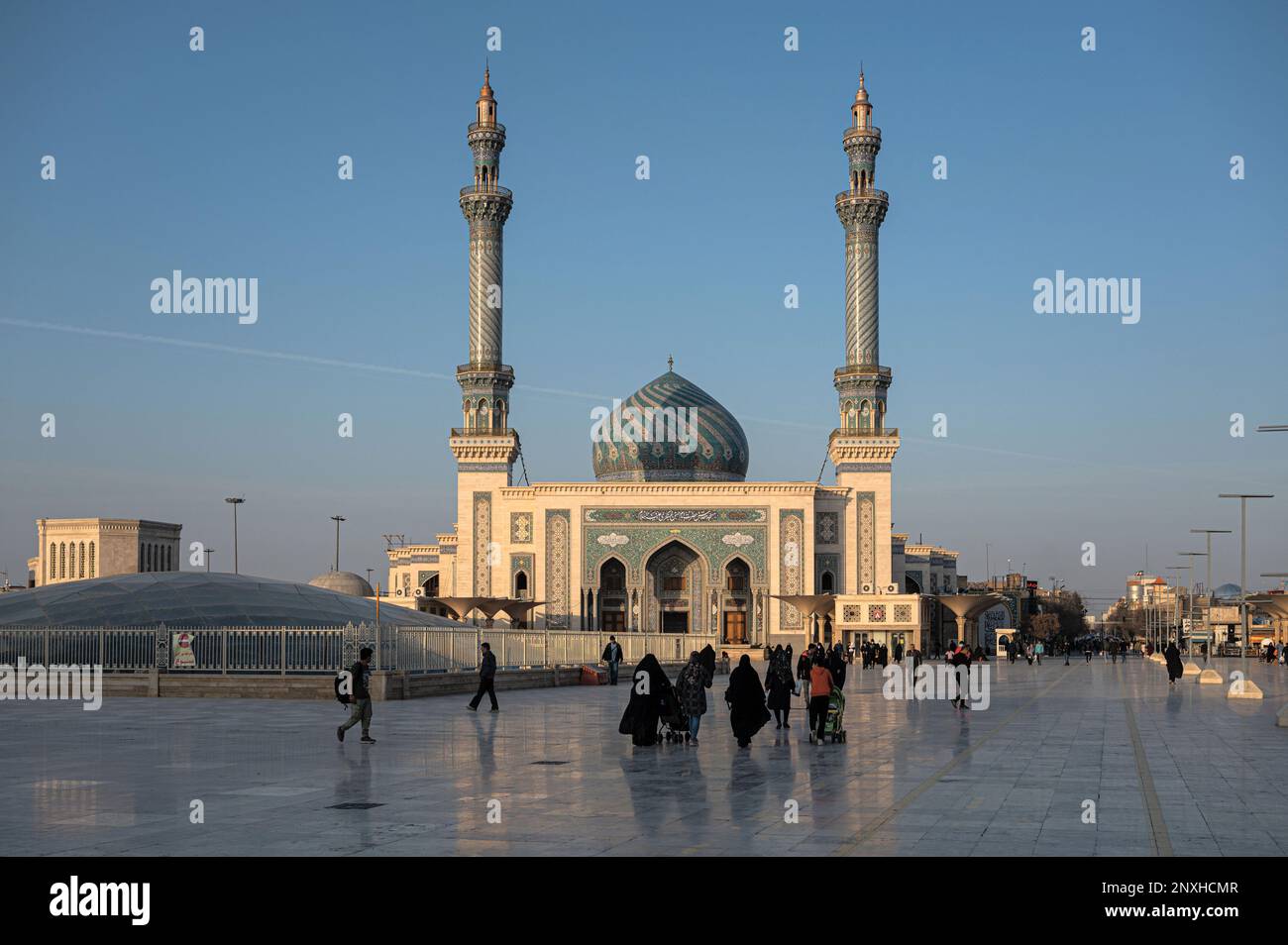 Ghom, Iran. 01st Mar, 2023. People walk along in the light of the ...