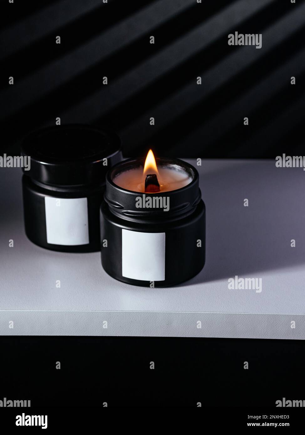 The candle is on a white shelf, black background with highlights Stock ...