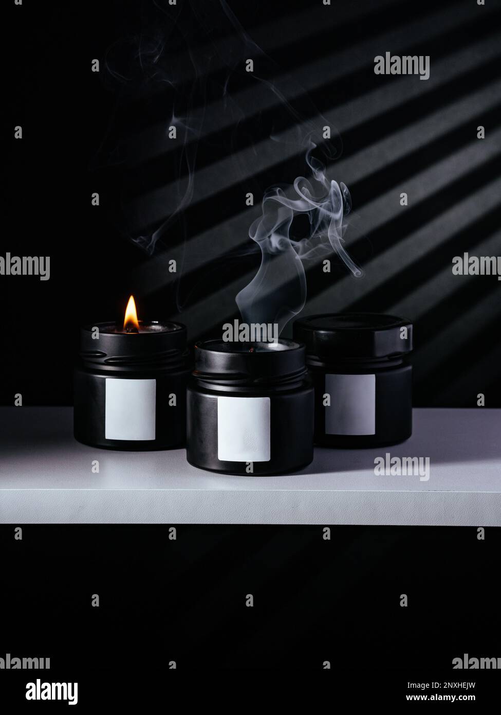 The candle is on a white shelf, black background with highlights Stock ...