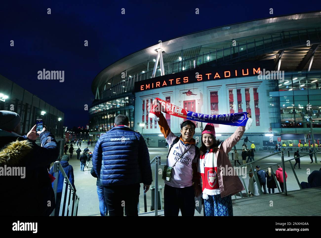 Arsenal fans pose for pictures with a match half and half scarf outside ...