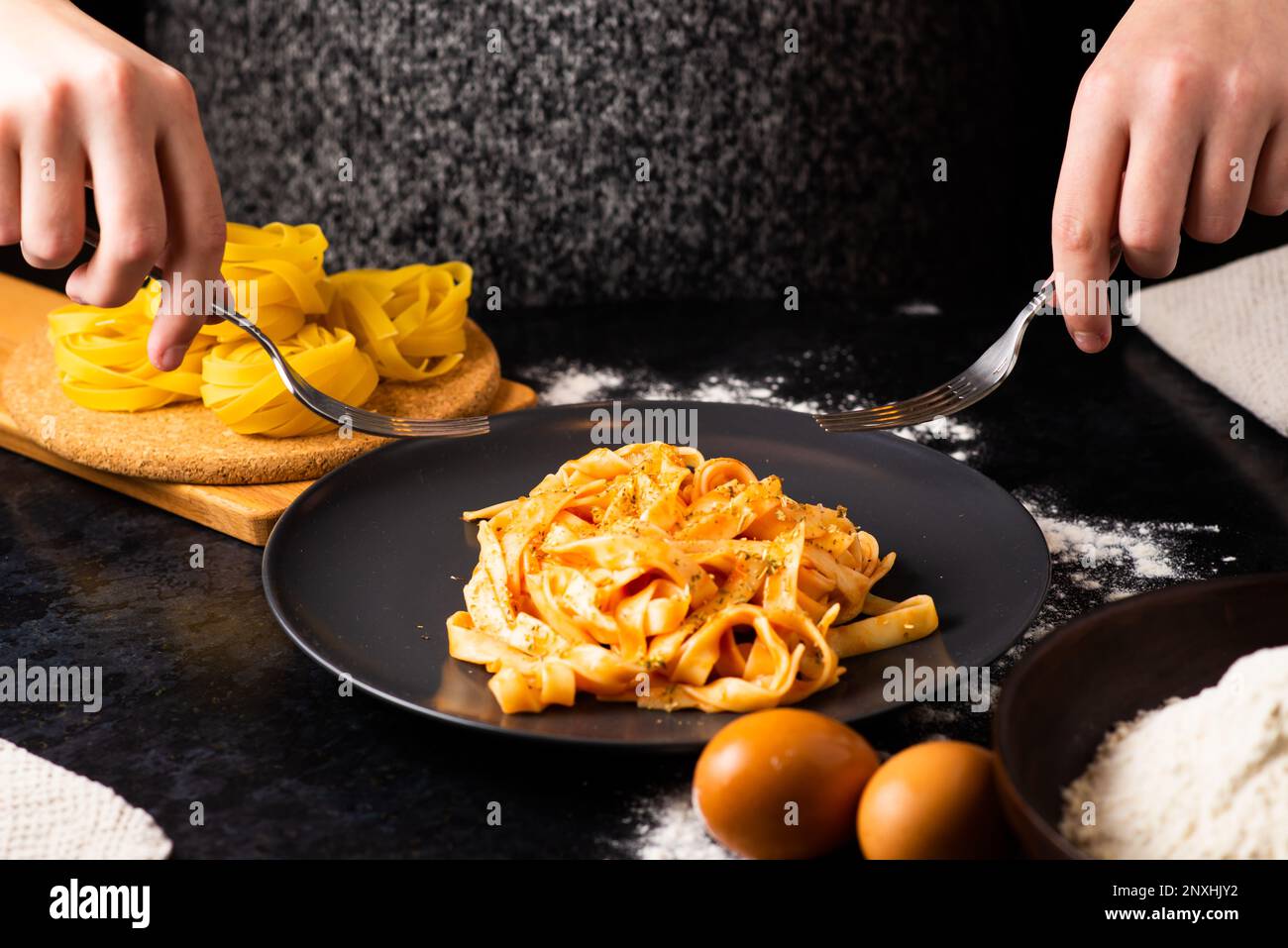 A close-up of hands holding a fork, digging into a plate of fast food ...