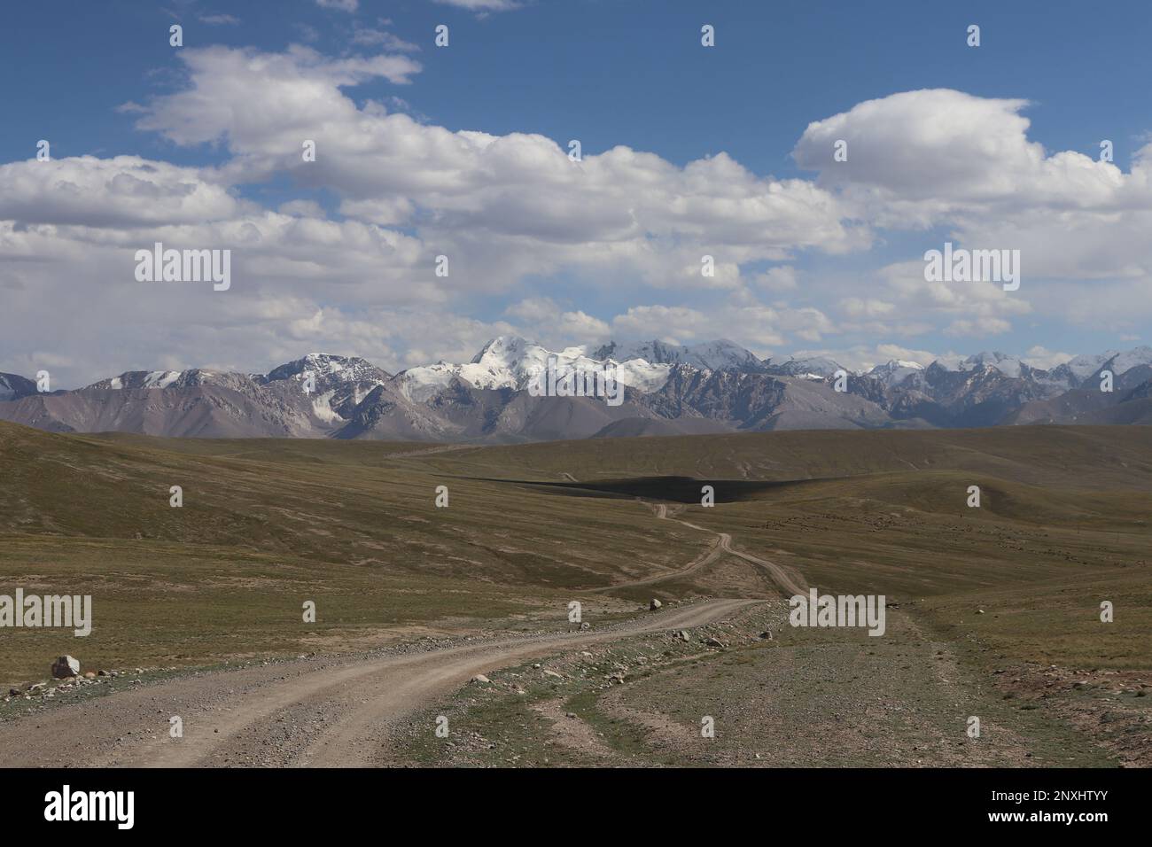 bumpy and empty road in front of a snow covered mountain range in ...