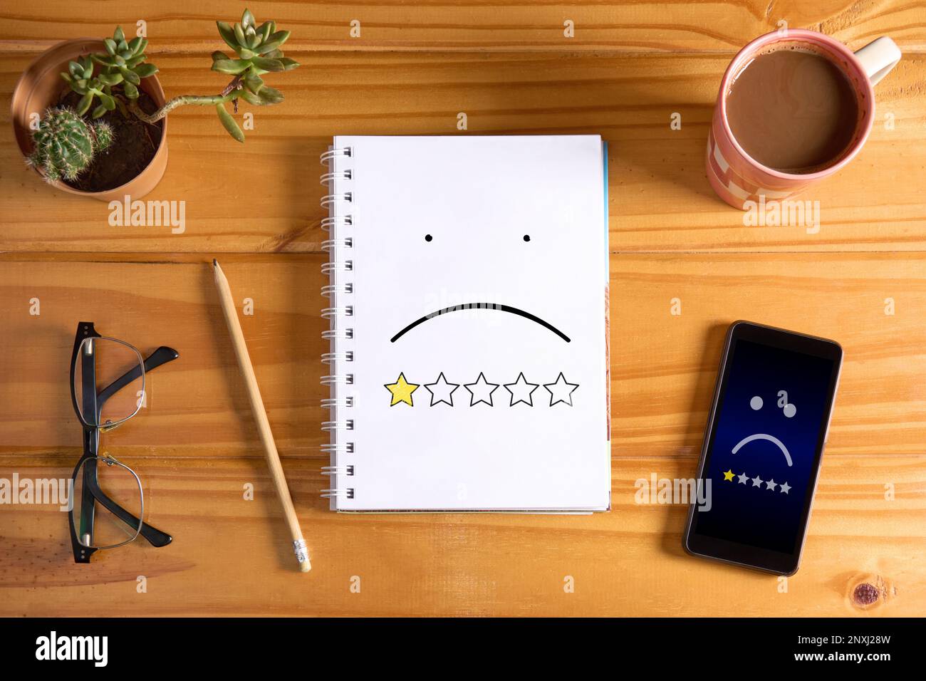 Top view of notebook with sad face and one star rating on table with ...