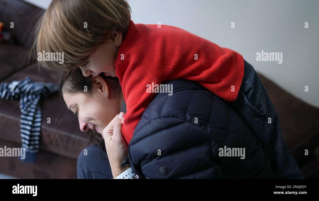 Child embracing mother back. Little boy jumping on parent surprise ...