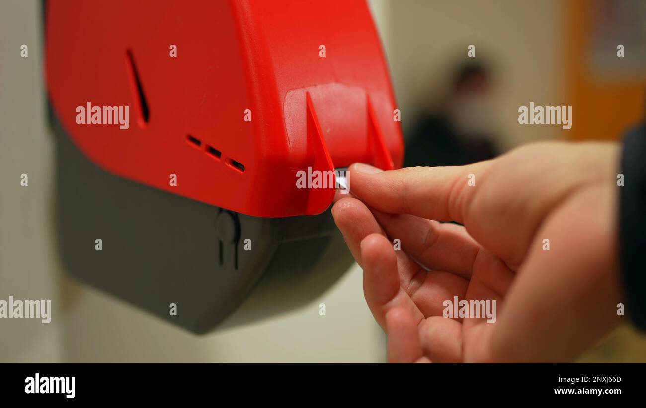 Closeup of Waiting Number Machine. Customer hand pulls a numbered ...