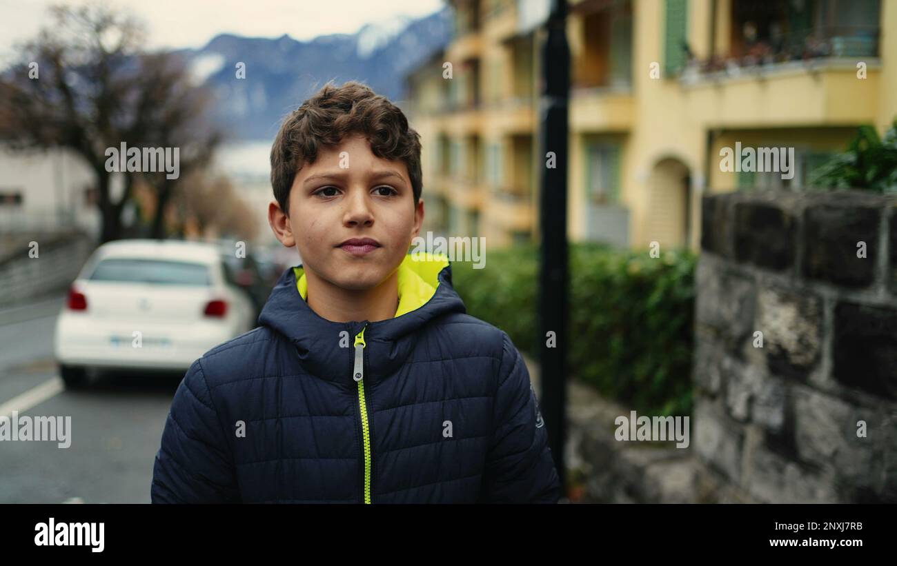Portrait of a pensive preteen male kid walks in city street. Young boy ...