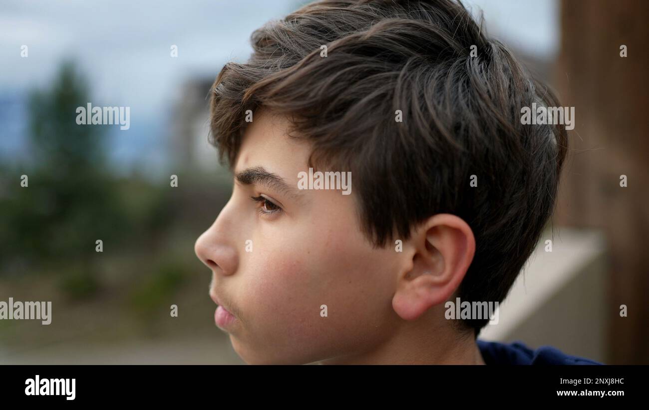 Teen kid stands at park outside staring at horizon in meditation ...