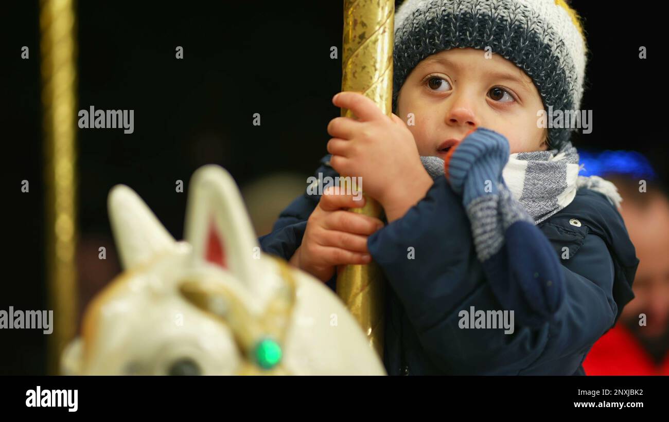 One happy child riding carousel at moving merry go round. Small boy ...