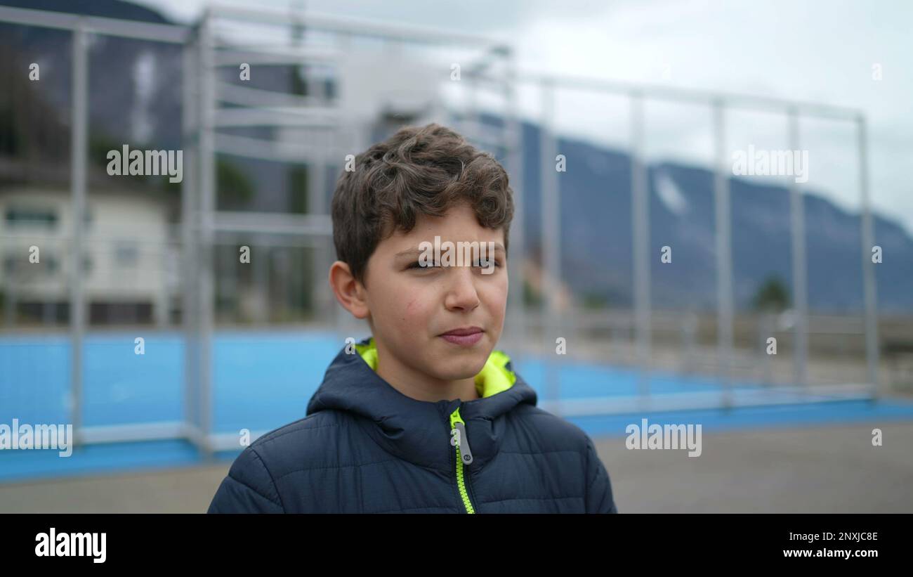 One pensive young boy standing outside thinking. Thoughtful Kid wearing ...