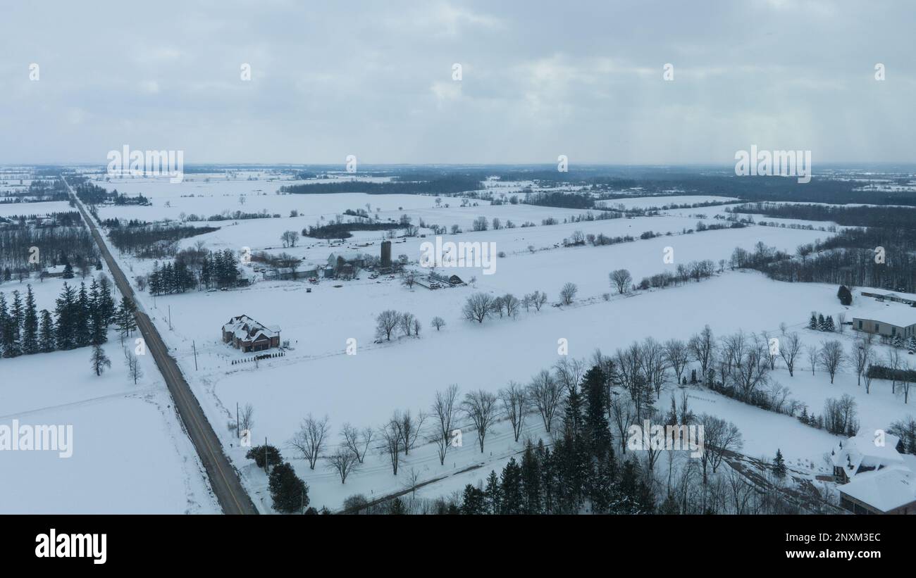 A vast, snow-covered rural landscape is seen from a high-angle aerial ...