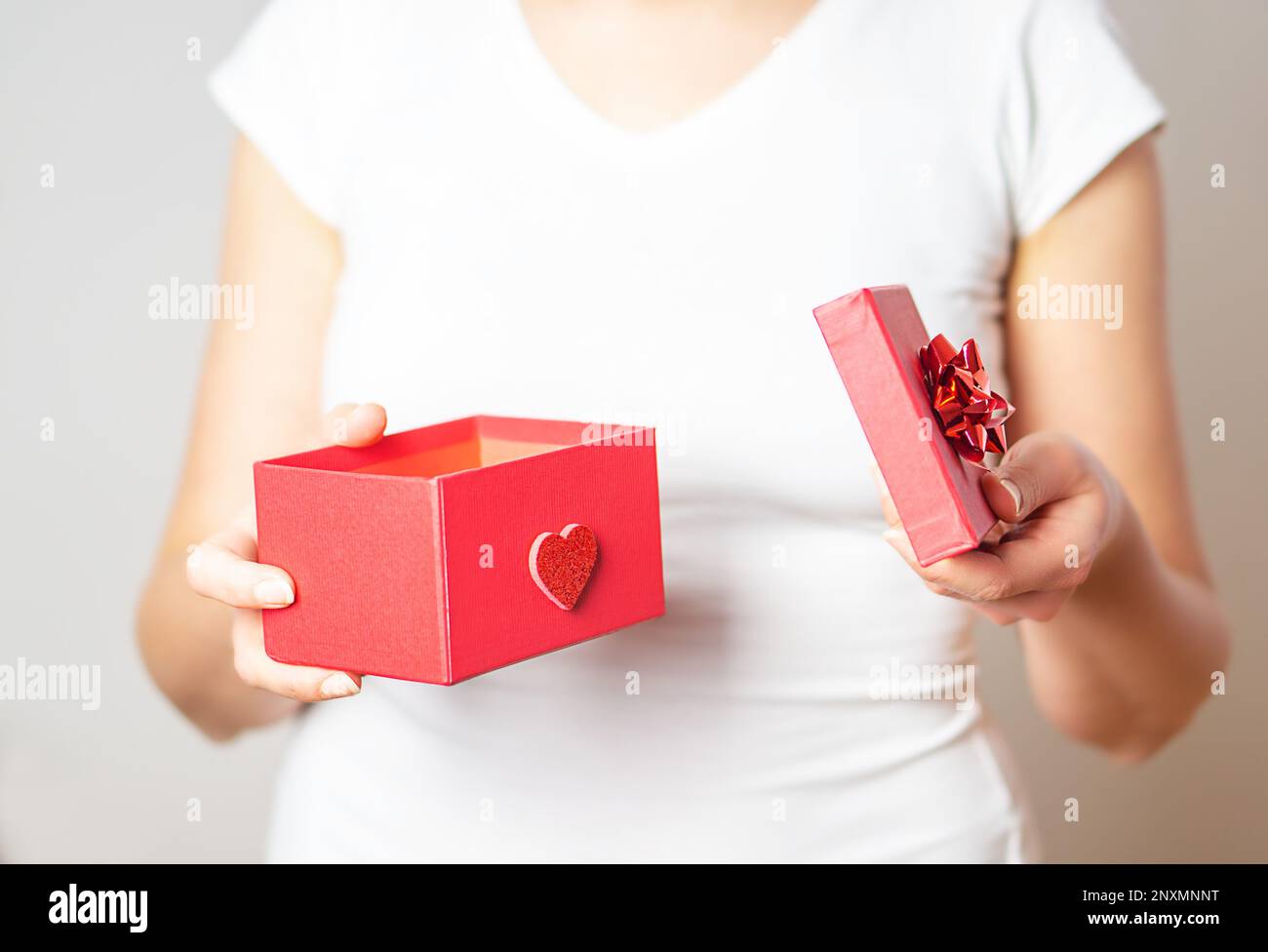 Close up shot of the female hands opening a small gift in a red box ...
