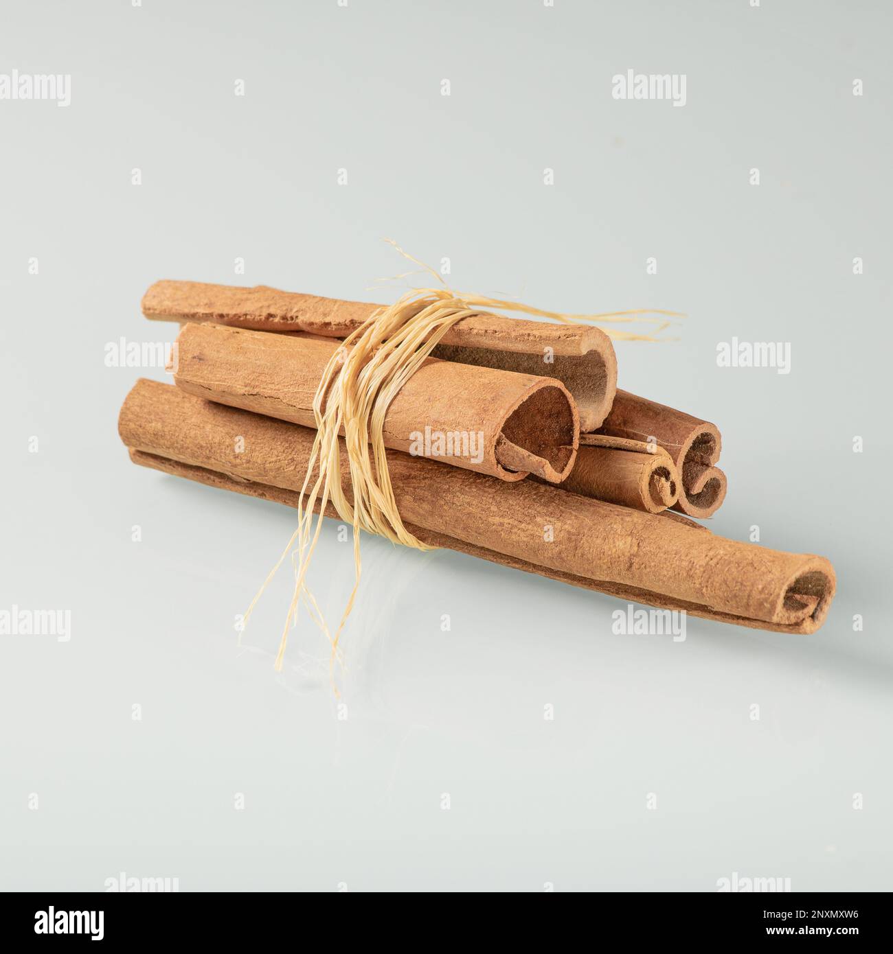 Bunch of cinnamon sticks on a light background with reflection in a ...