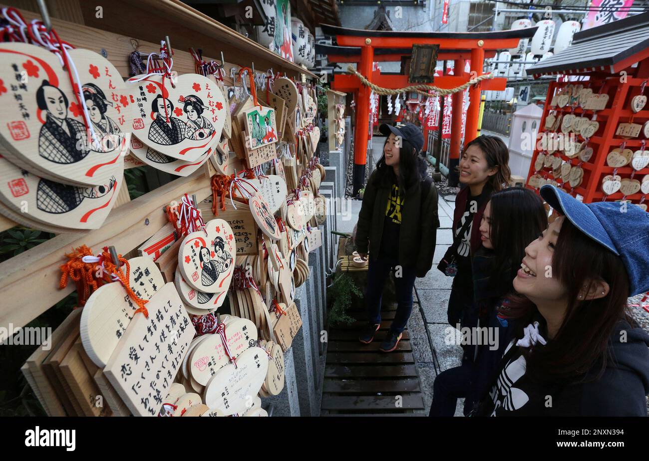 Women hang wooden plaque (ema) charms that their wishes are written on ...