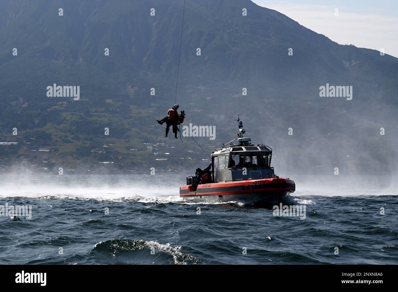 A Japan Coast Guard Mobile Rescue Technician hoists a simulated swimmer ...