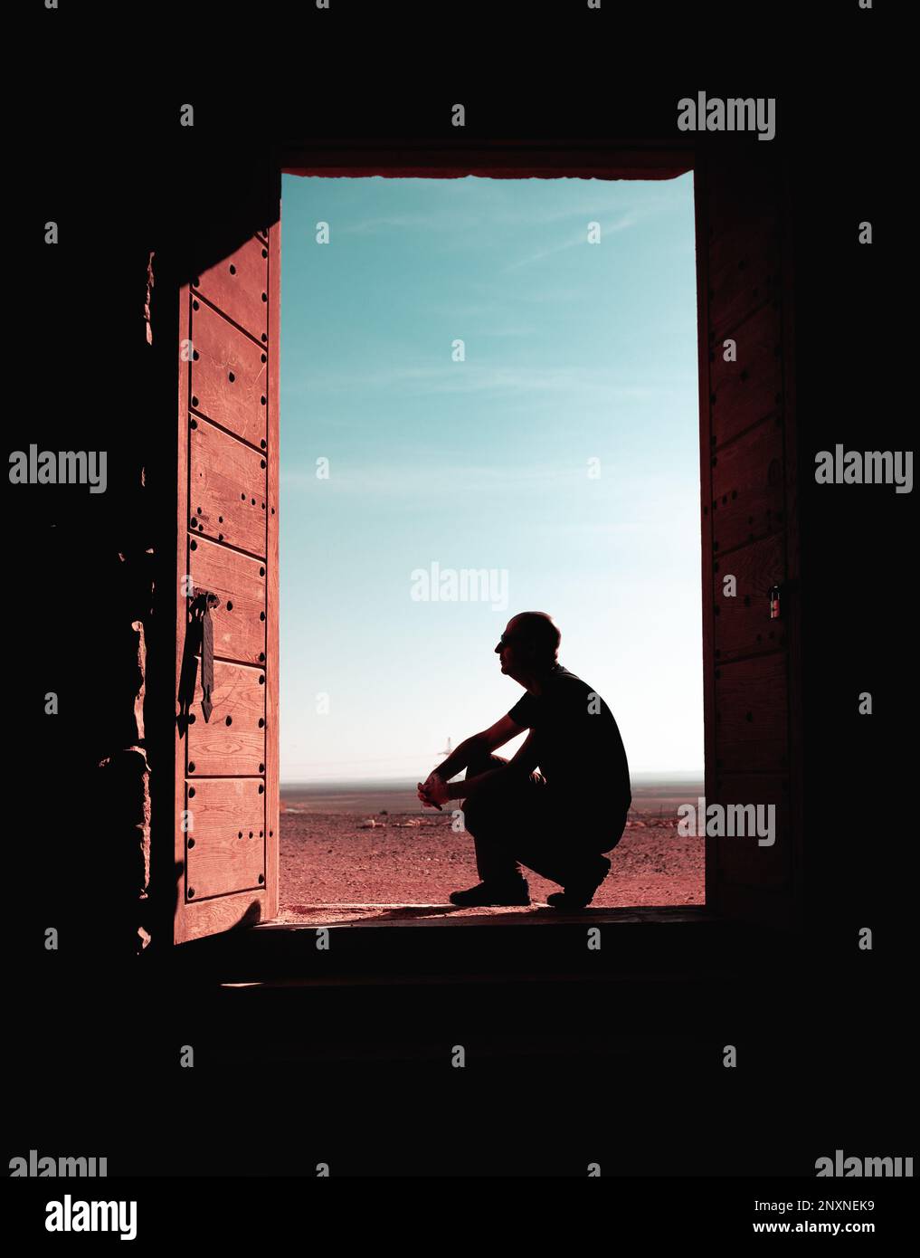 Silhouette of Man Crouching in Doorway of Ancient Site Stock Photo - Alamy