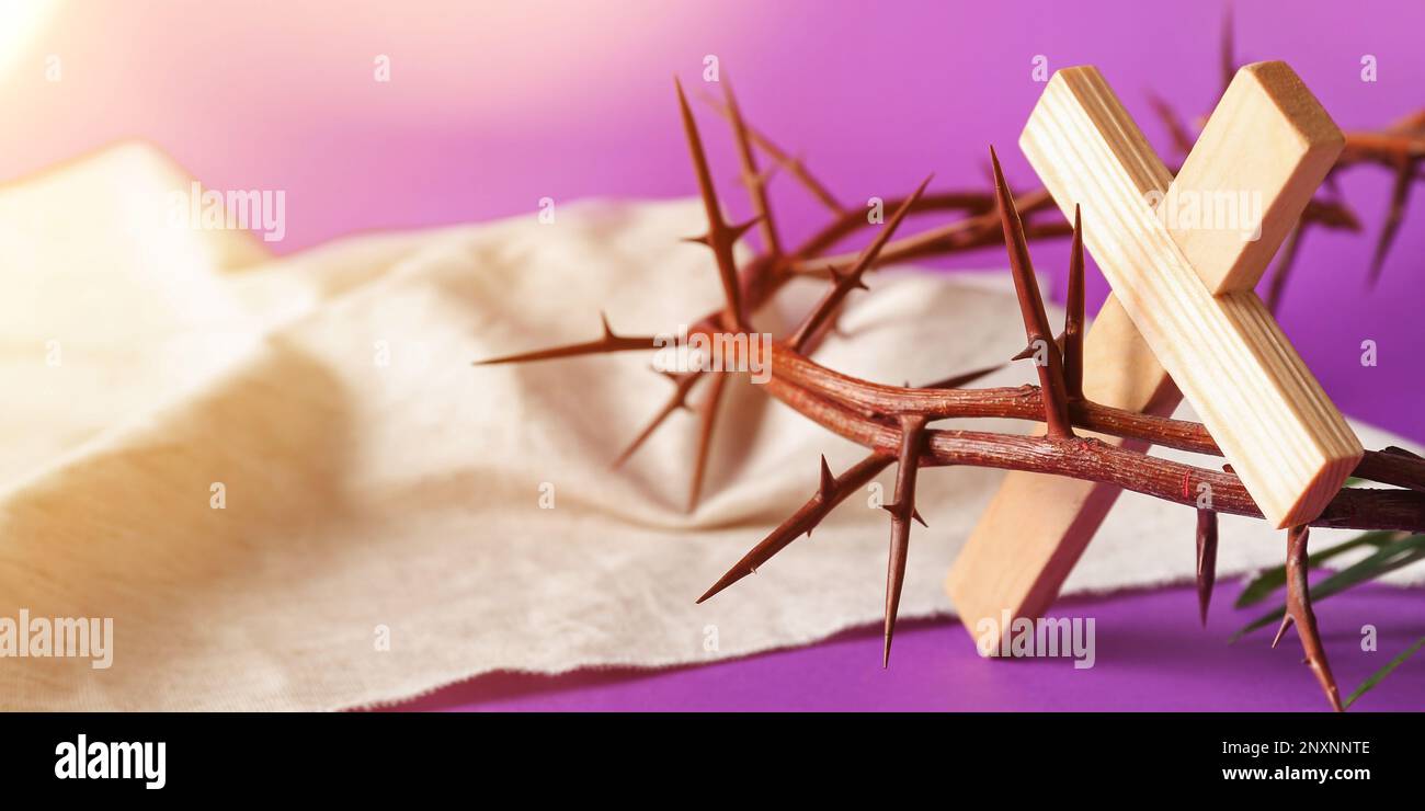 Crown of thorns, wooden cross and shroud on purple background, closeup ...