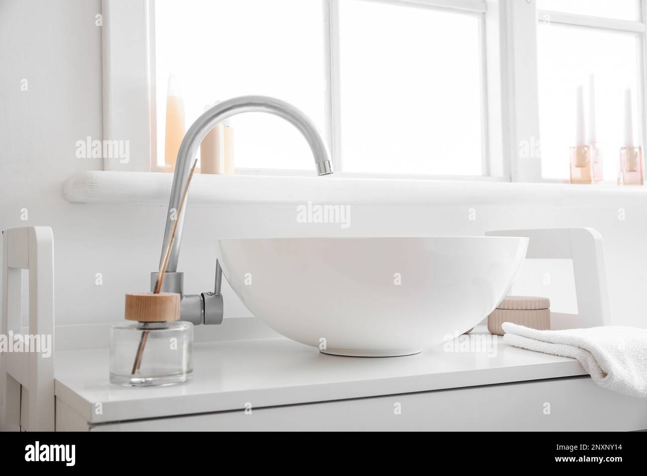 Interior of bathroom with ceramic sink and reed diffuser near window ...