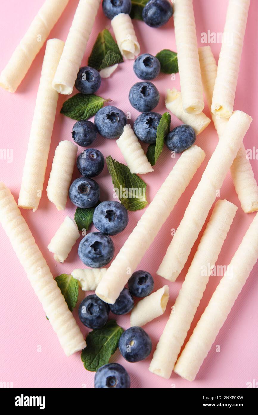 Delicious wafer rolls, blueberries and mint on pink background Stock ...