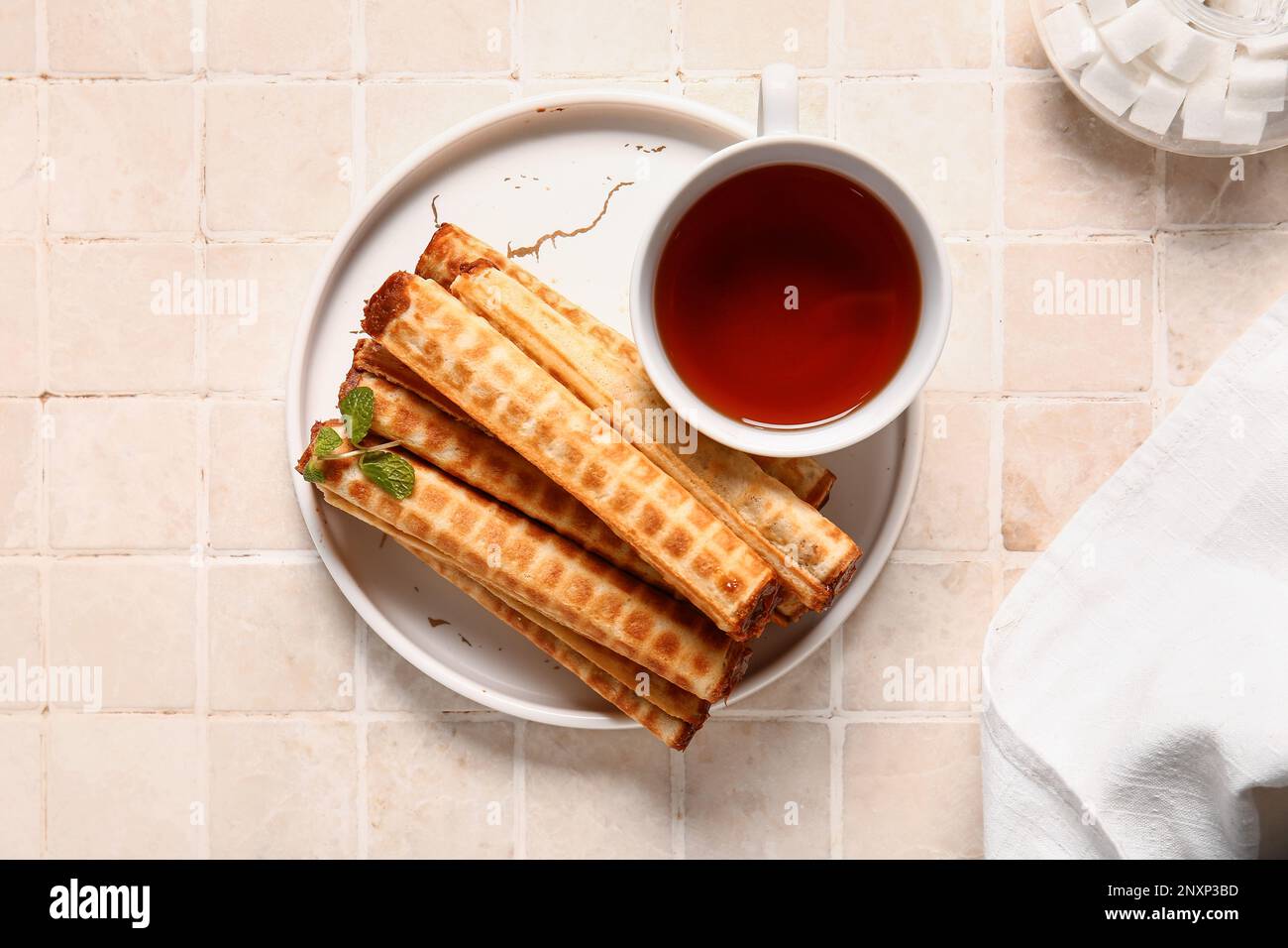 Plate of wafer rolls with boiled condensed milk and cup of black tea on ...