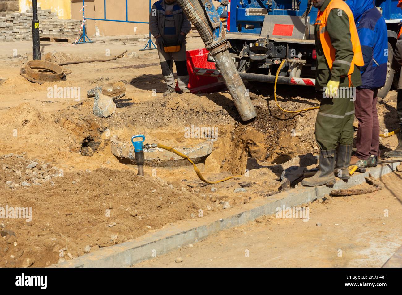 Workers use a suction excavator based on a truck to sample soil in a ...