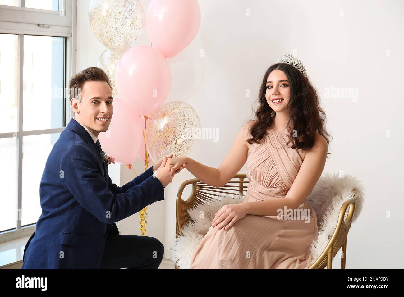Teenage boy standing on one knee in front of his prom date at home ...