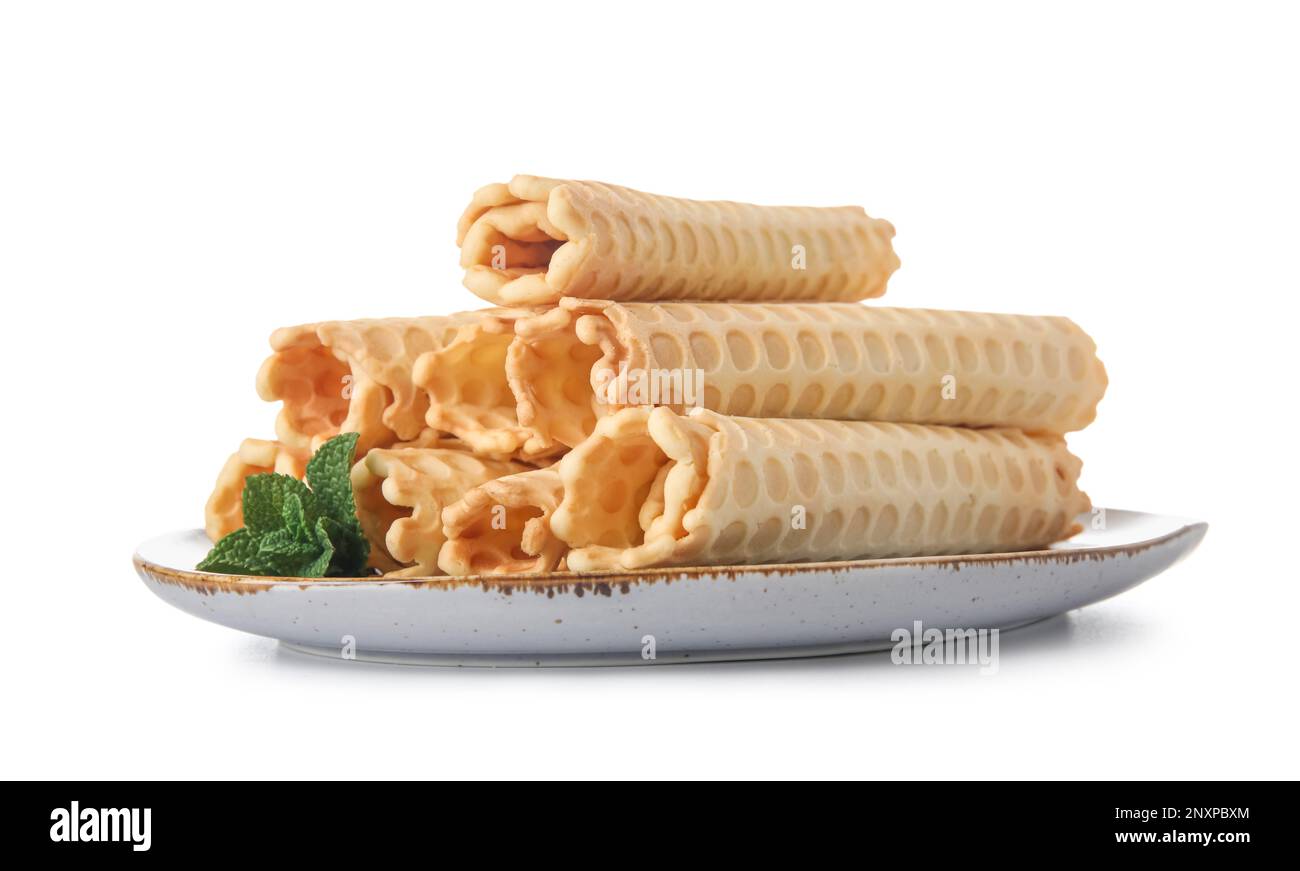Plate with stack of delicious wafer rolls and mint isolated on white ...