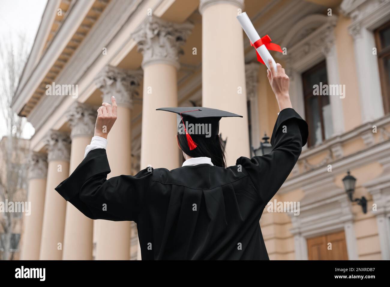 Student with diploma after graduation ceremony outdoors, back view ...