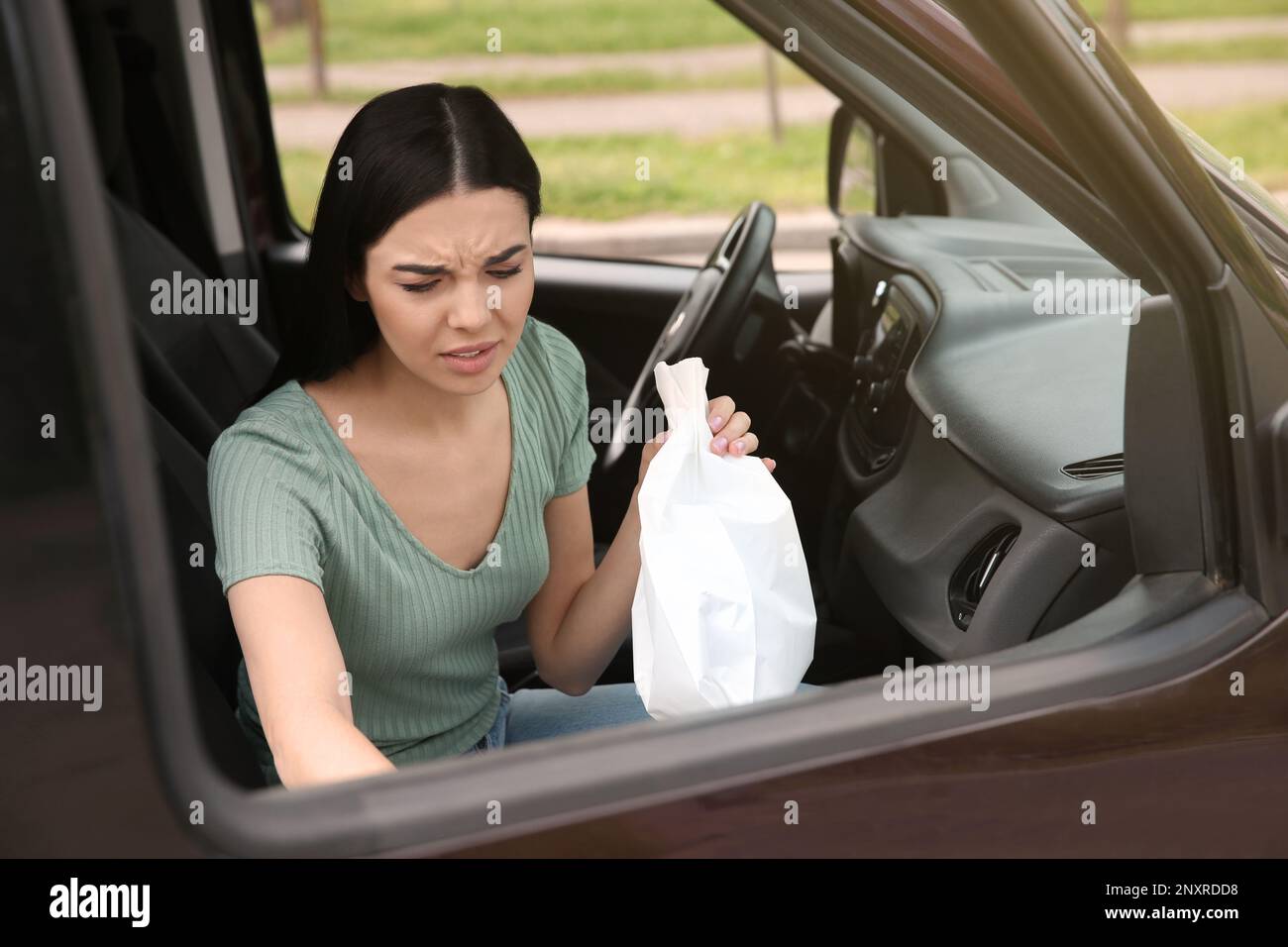 Young woman with paper bag suffering from nausea in car Stock Photo - Alamy