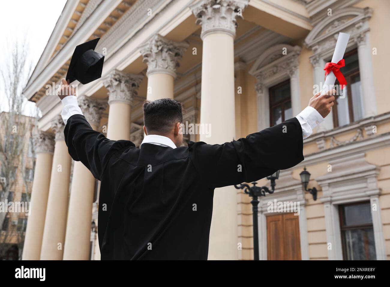 Student with diploma after graduation ceremony outdoors, back view ...