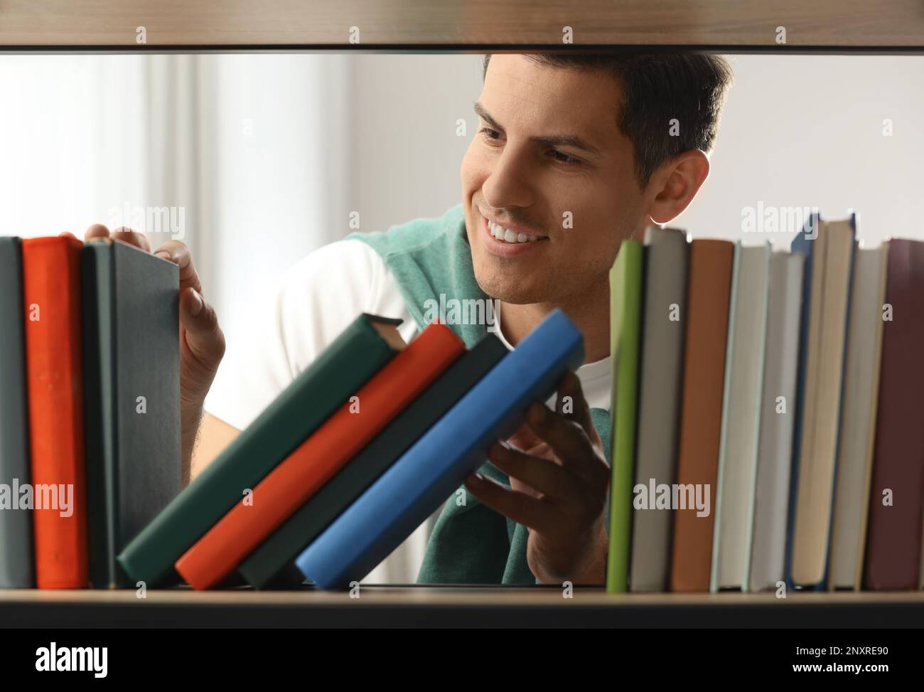 Man searching for book on shelf in library Stock Photo - Alamy
