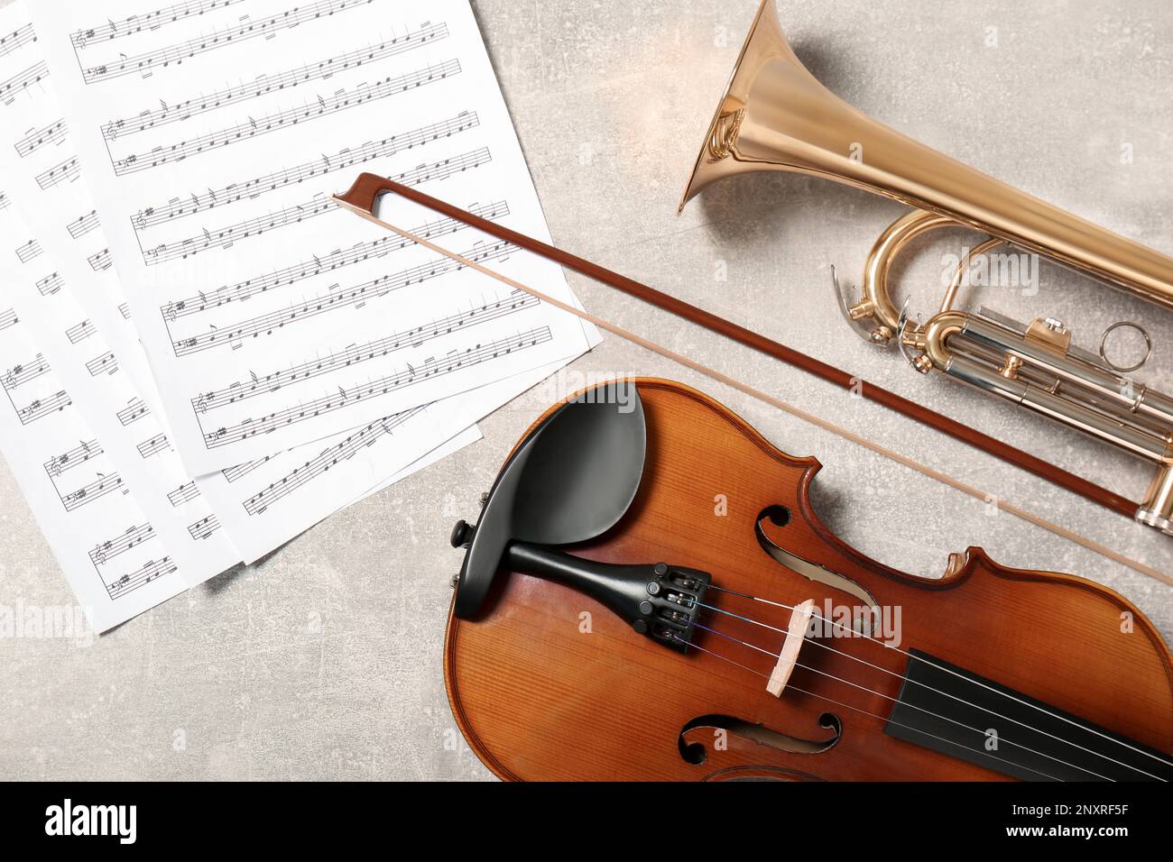 Violin, trumpet and note sheets on light grey background, flat lay ...