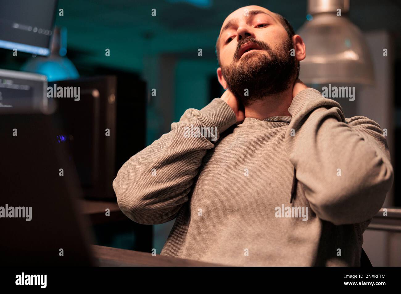 Tired male coder dealing with back pain and pressure, working late at night and feeling tense ...