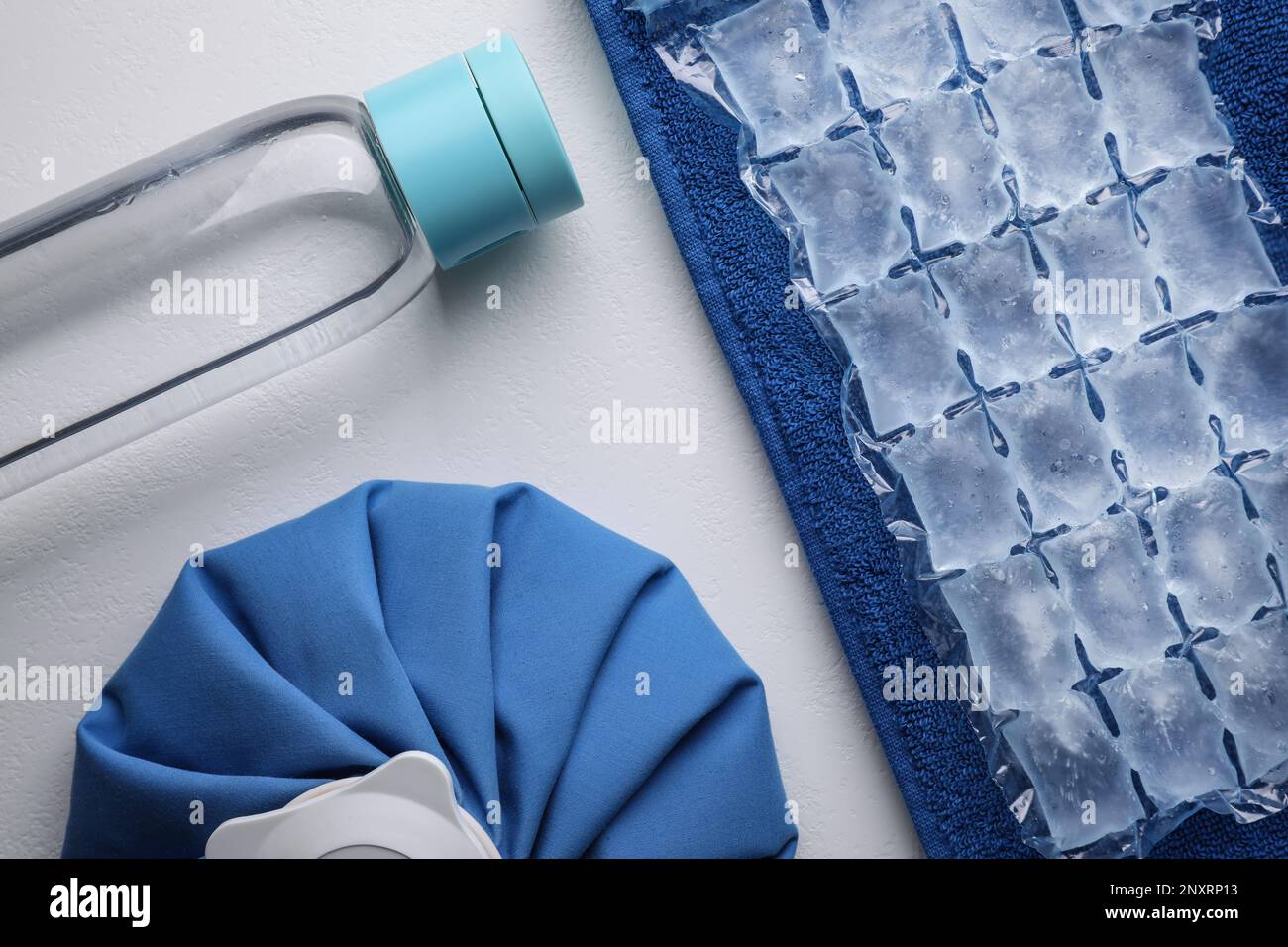 Bottle of water, ice pack, cold compress and towel on white background ...