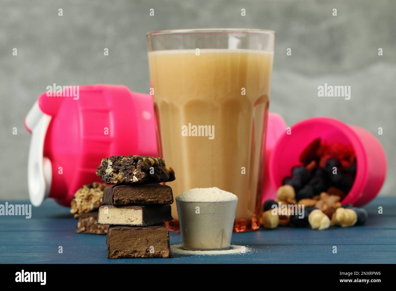 Different energy bars, protein cocktail and powder on blue wooden table ...