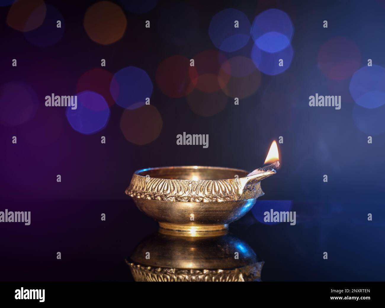 Lit diya on dark background with blurred lights, space for text. Diwali ...