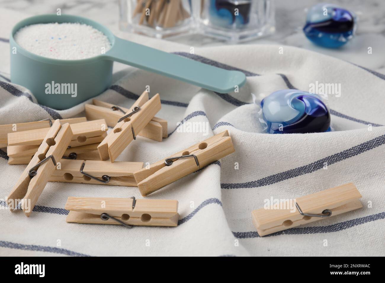Wooden clothespins, detergent laundry pods and powder on fabric ...