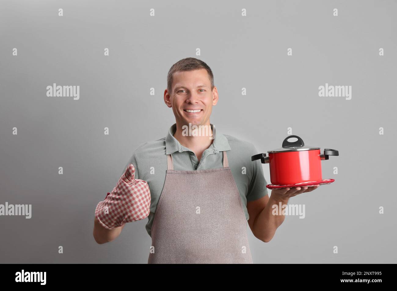 Happy man with cooking pot on light grey background Stock Photo - Alamy